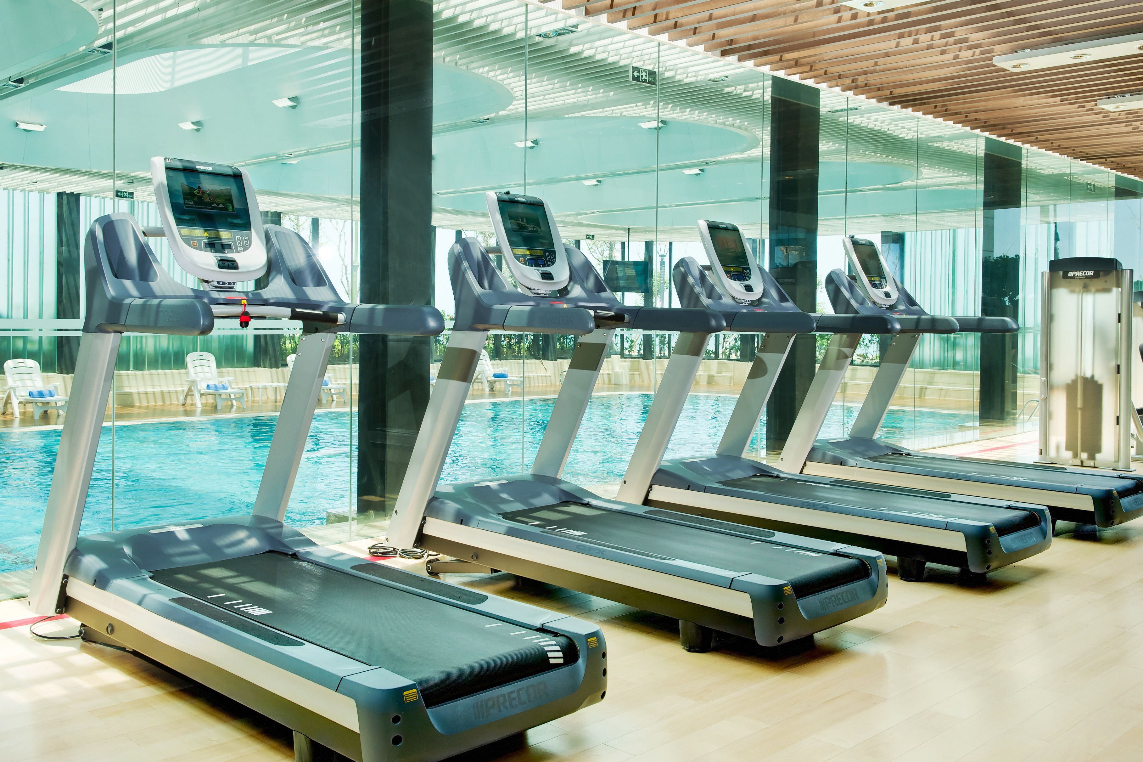 Uma academia com esteiras, piscina e design de interiores moderno.