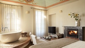 Quarto de hotel moderno com uma banheira grande, televisão de tela plana, lareira e uma cama confortável.