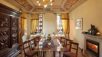 Uma sala de jantar com uma mesa de vidro, cadeiras de madeira e uma lareira.