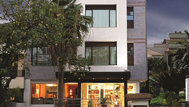 Um hotel moderno com fachada plana, grandes janelas e entrada visível com escadaria que leva ao saguão.