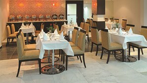 Um restaurante com várias mesas e cadeiras, parede estampada e design de interiores moderno.
