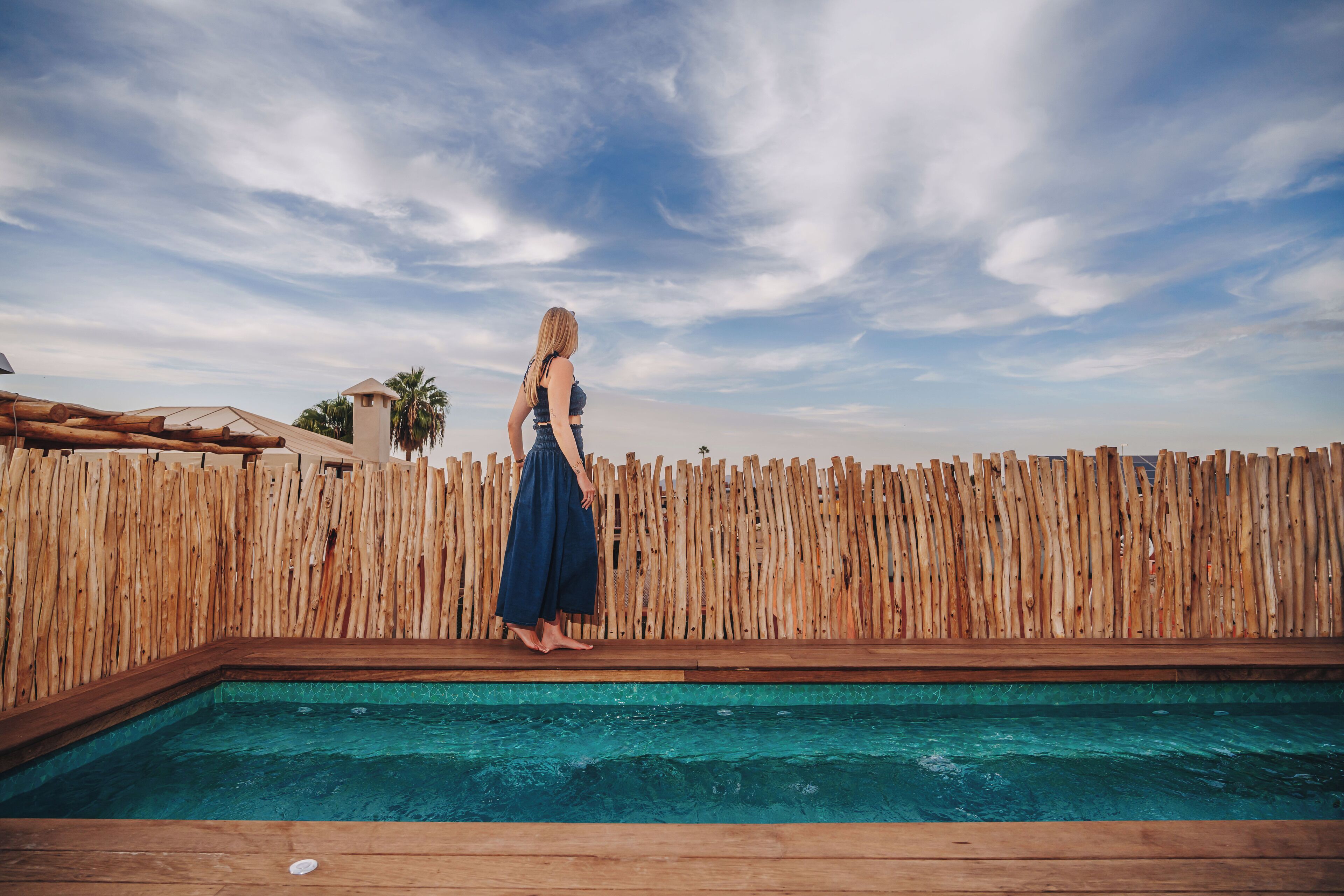 Uma piscina com um deck de madeira e uma cerca de madeira ao fundo.