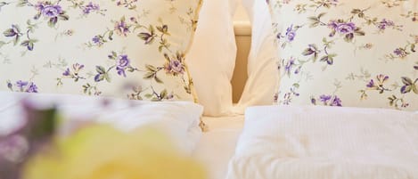 Cama com roupa de cama estampada em floral e travesseiro branco.