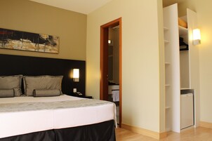 Quarto com cama, mesa de cabeceira, pintura e armário com luz.