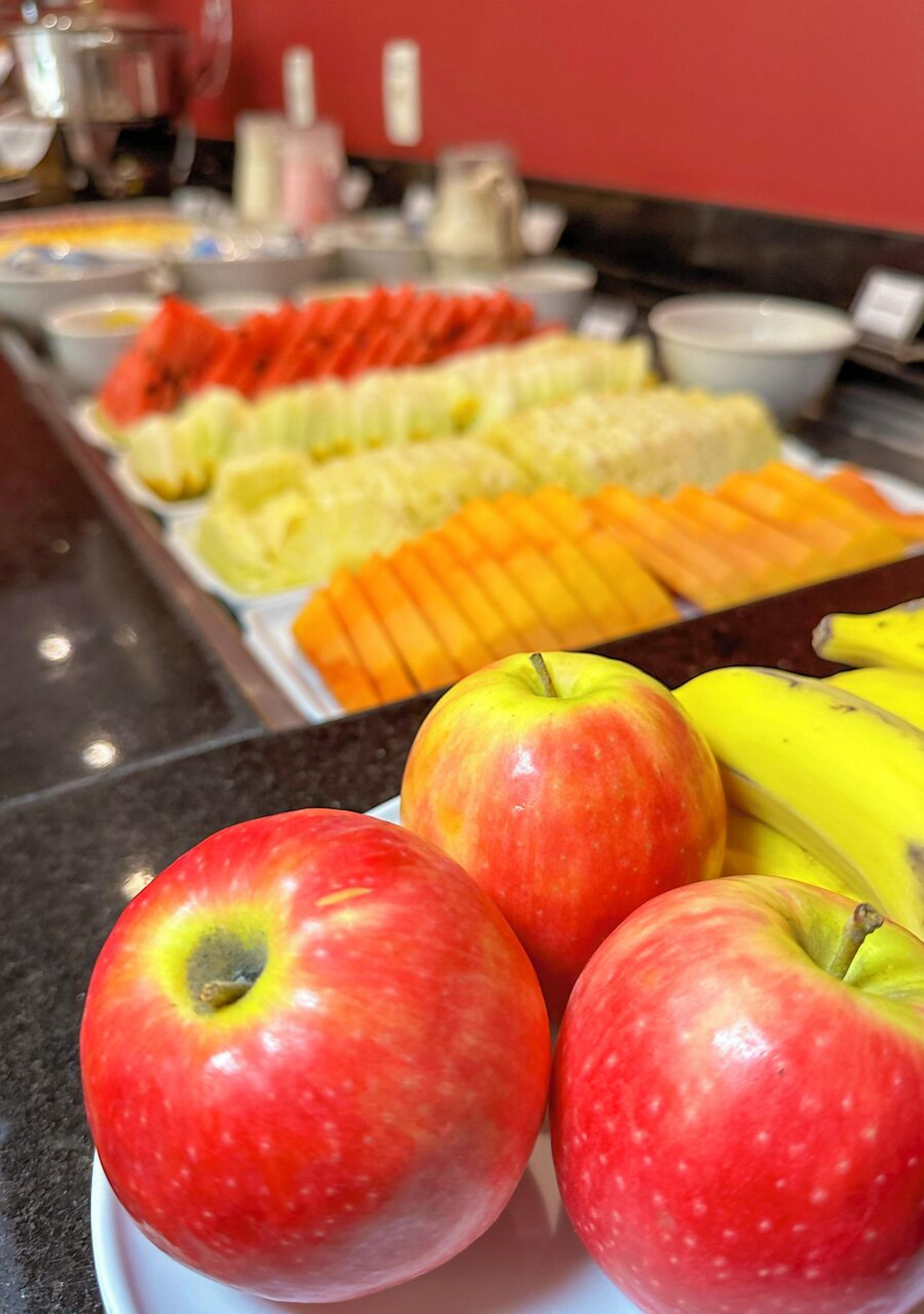 Um buffet com diversas frutas e legumes, incluindo maçãs, bananas e cenouras.