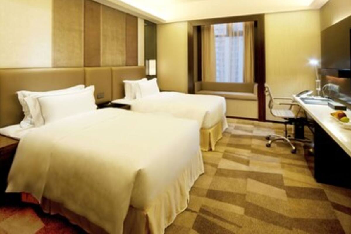 Quarto de hotel com duas camas, uma escrivaninha e uma cadeira.