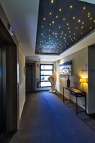Corredor de hotel com teto estrelado, um extintor de incêndio, uma escultura e um quadro na parede.