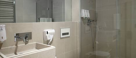 Um banheiro moderno com pia, vaso sanitário e chuveiro com divisória de vidro.