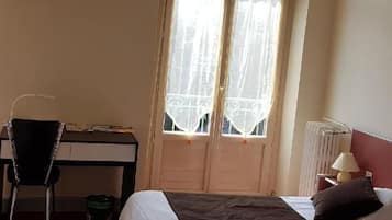 Quarto de hotel com duas camas, uma escrivaninha com cadeira, um radiador e uma televisão na parede.