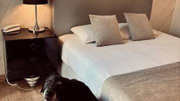 Quarto com cama, luminária de cabeceira, mesa de cabeceira e um cão.