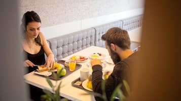 Um ambiente de café da manhã com mesa, cadeiras e um banco acolchoado.