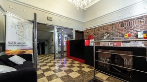 Uma área de recepção de hotel com chão xadrez, um balcão de recepção preto e um mapa na parede.