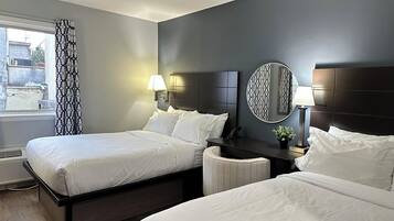 Quarto de hotel com duas camas, uma mesa de cabeceira com luminária, espelho fixado na parede e janela com cortinas.