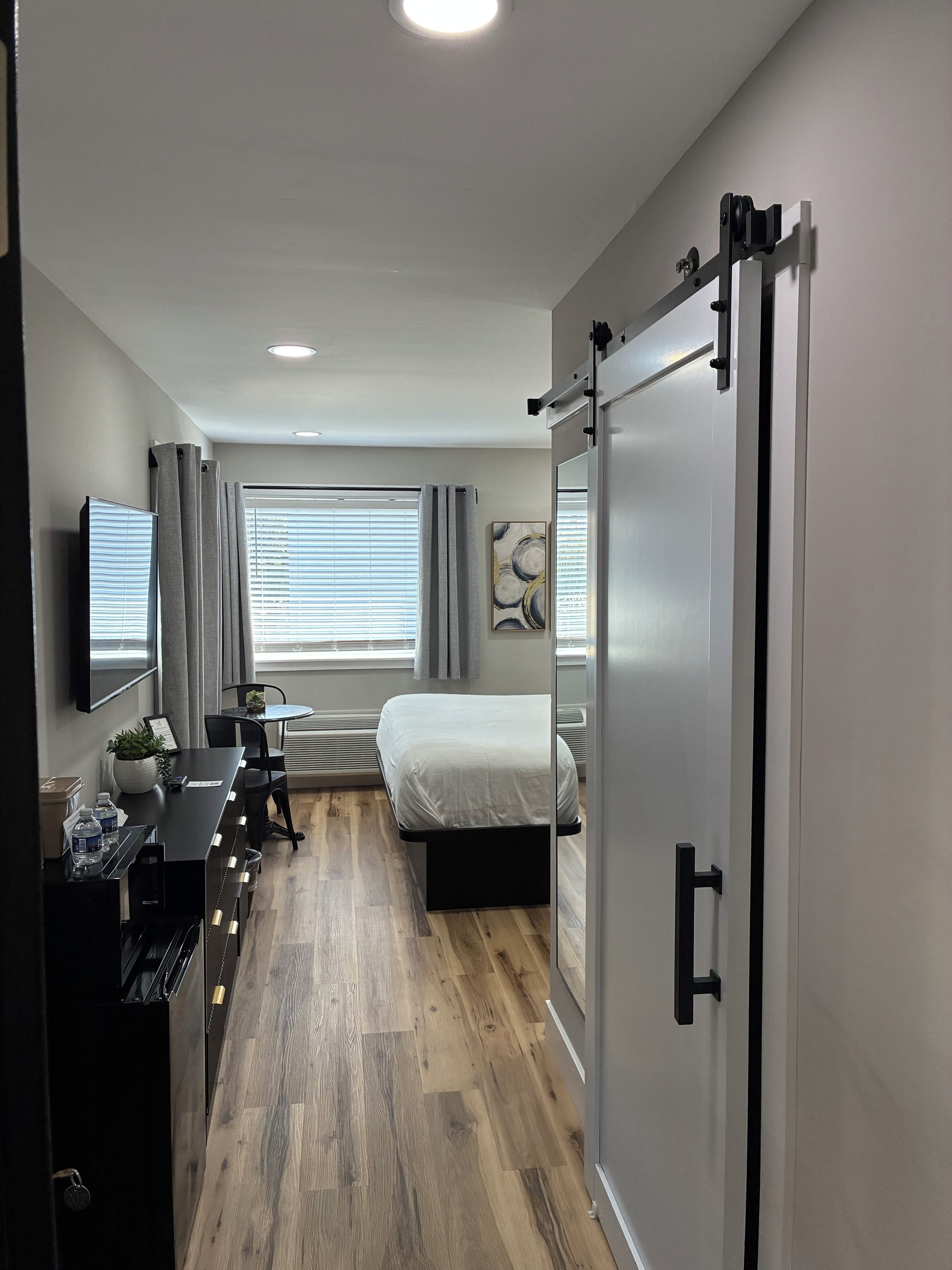 Quarto moderno com cama, mesa de cabeceira e escrivaninha com cadeiras.