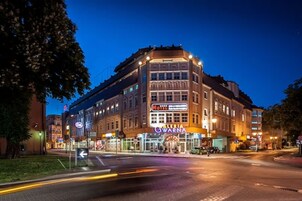 Um hotel com estilo arquitetônico europeu clássico, apresentando uma entrada de canto imponente e uma placa com o nome 'Hotel Gwara'.