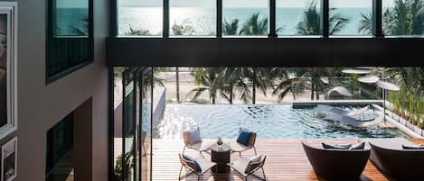 Um deck moderno ao ar livre com vista para o mar, piscina e espreguiçadeiras.