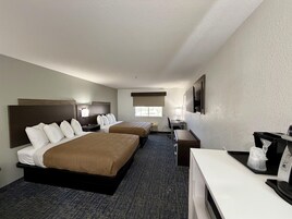 Quarto de hotel com duas camas, uma escrivaninha, uma cadeira, uma TV e uma janela.