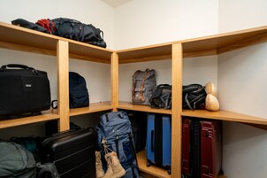 Um espaço de armazenamento em canto com prateleiras exibindo diferentes tipos de bagagem, como malas, mochilas e sacos.