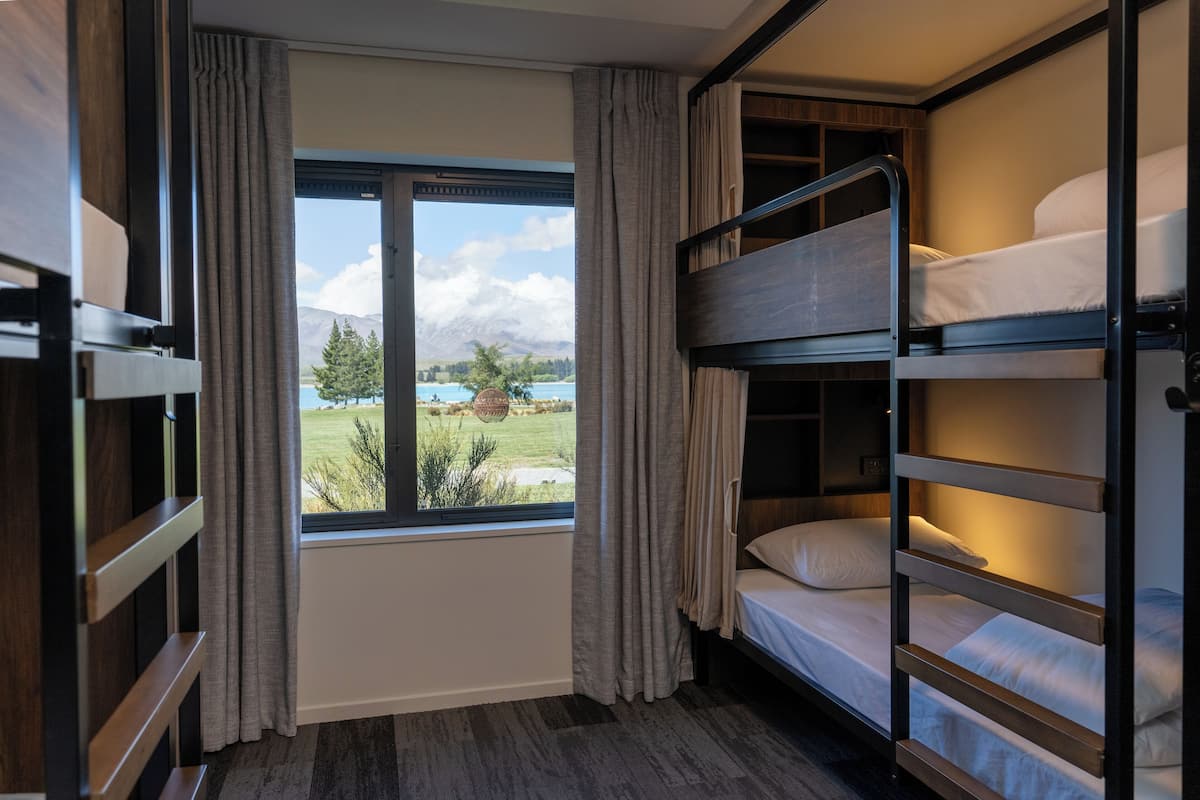 Quarto com beliche e vista para um lago e montanhas.