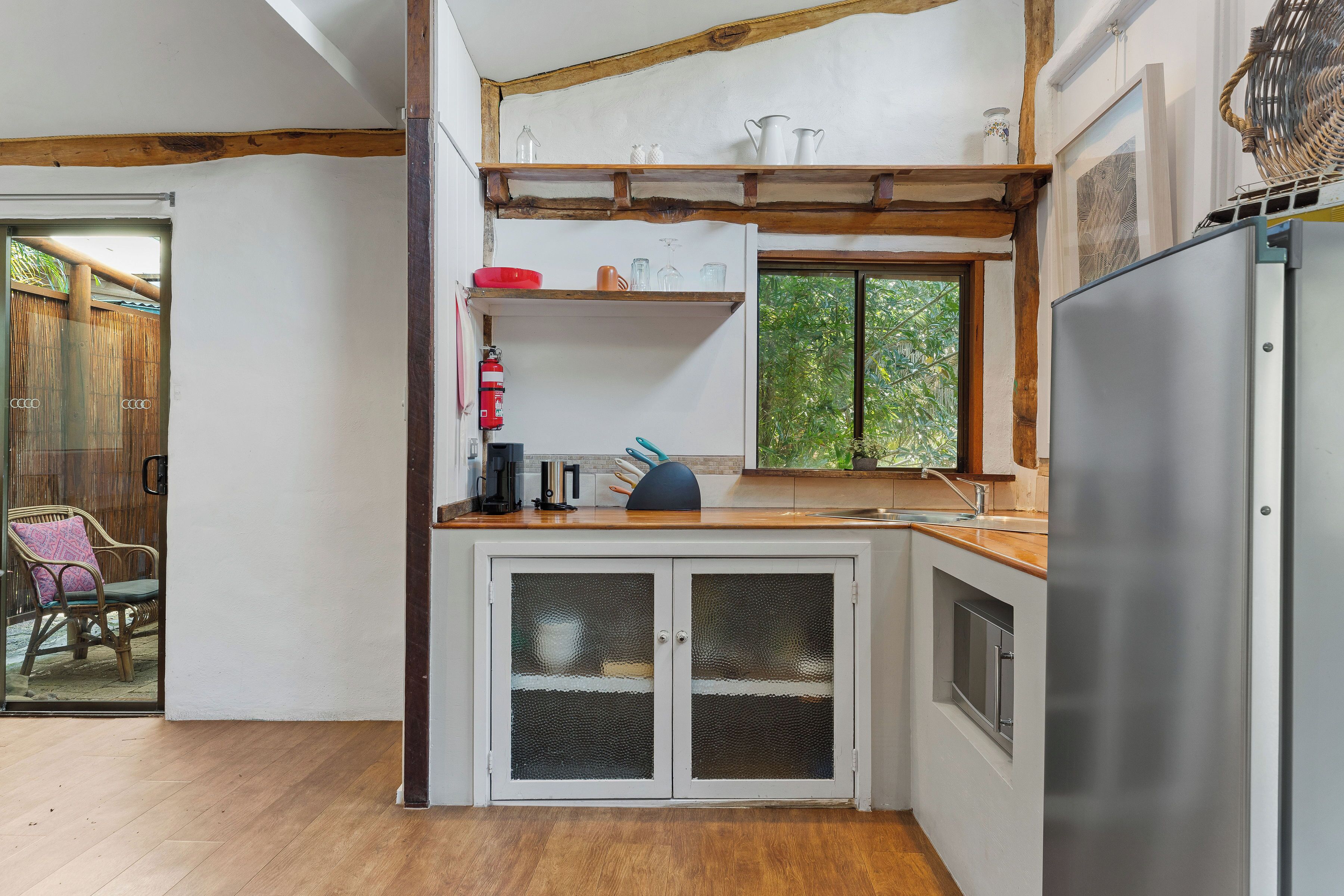 Cozinha compacta com bancada de madeira, geladeira embutida e janela que traz luz natural.