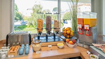 Um buffet de café da manhã com diversos alimentos e um dispensador de sucos.