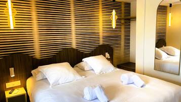 Quarto de hotel com uma cama grande, duas mesas de cabeceira, um criado-mudo, um espelho e uma parede com ripas horizontais.