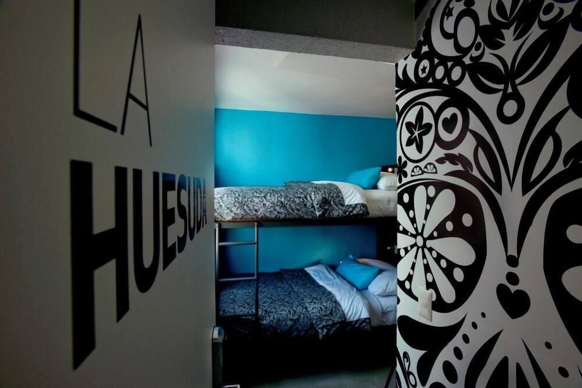 Quarto com beliches, parede azul e cortina estampada.