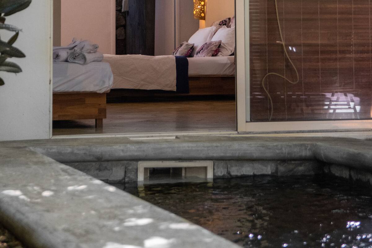 Decoração moderna com cama, uma pequena mesa e área de chuveiro.