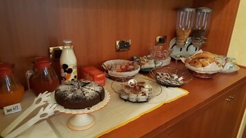 Um buffet de café da manhã com diversas opções de comida, incluindo um bolo de chocolate, doces e bebidas.