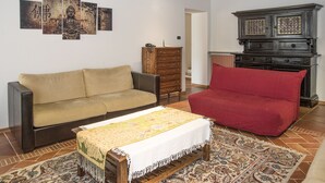 Sala de estar com sofá bege, sofá vermelho, um aparador de madeira e um tapete estampado.