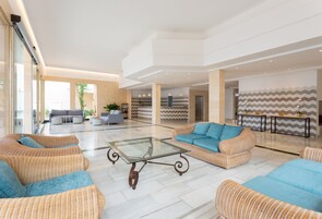 Um hall amplo com móveis de vime, uma mesa de centro de vidro e design de interiores moderno.