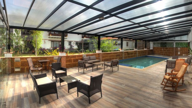 Um pátio externo com piscina, área de estar e estrutura de vidro.