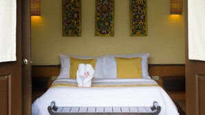 Quarto de hotel com cama, teto de madeira e três painéis decorativos na parede.