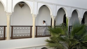 Pátio com arcos brancos e varanda com grade de ferro forjado.