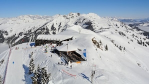 Montanha coberta de neve com teleférico e um chalé.