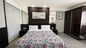 Quarto com cama, mesas de cabeceira, guarda-roupa e obras de arte nas paredes.