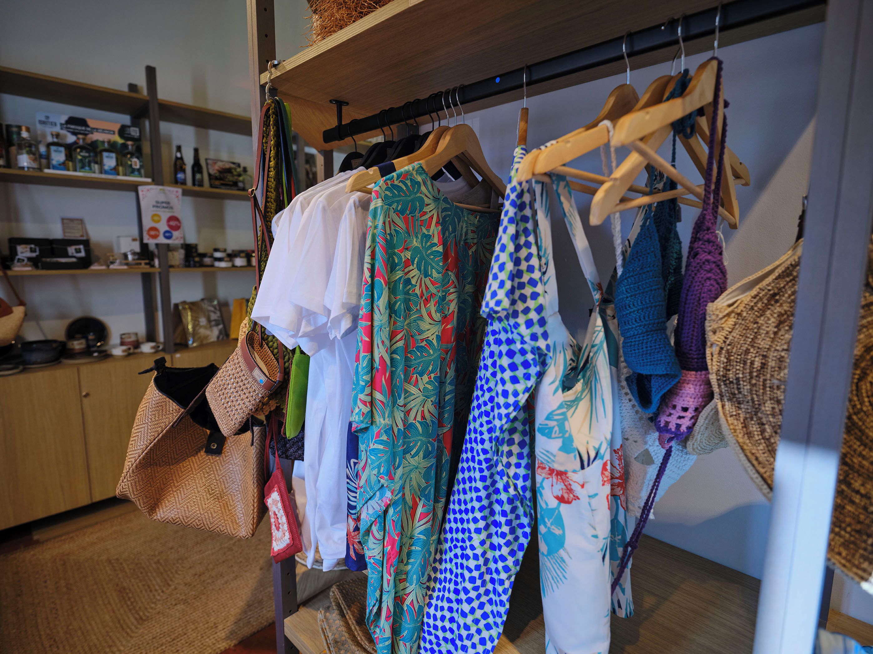 Um cabideiro com diversas peças de roupa e bolsas.