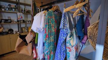 Um cabideiro com diversas peças de roupa e bolsas.