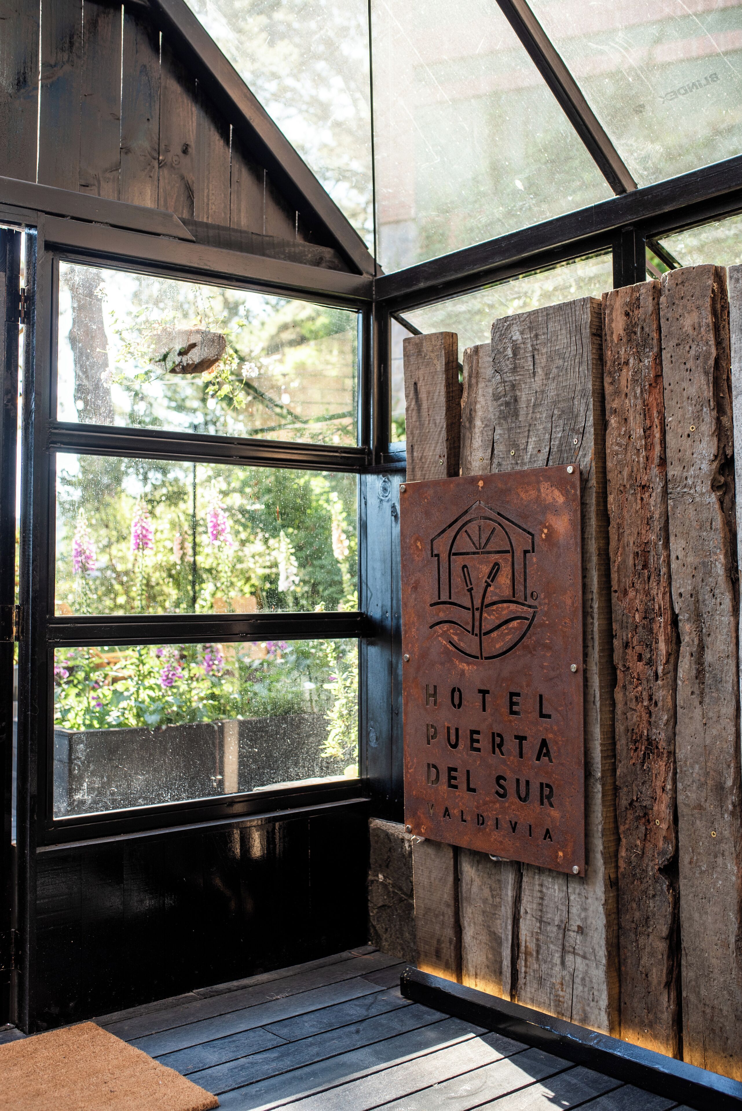 Uma placa de madeira com um logotipo e o texto 'Hotel Puerta del Sur Valdivia'.