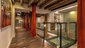 Um interior moderno com soalho de madeira, guarda-corpos de vidro e cortinas vermelhas.