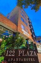 Placa do 122 Plaza Apartahotel, fachada moderna em tijolo e janelas iluminadas.