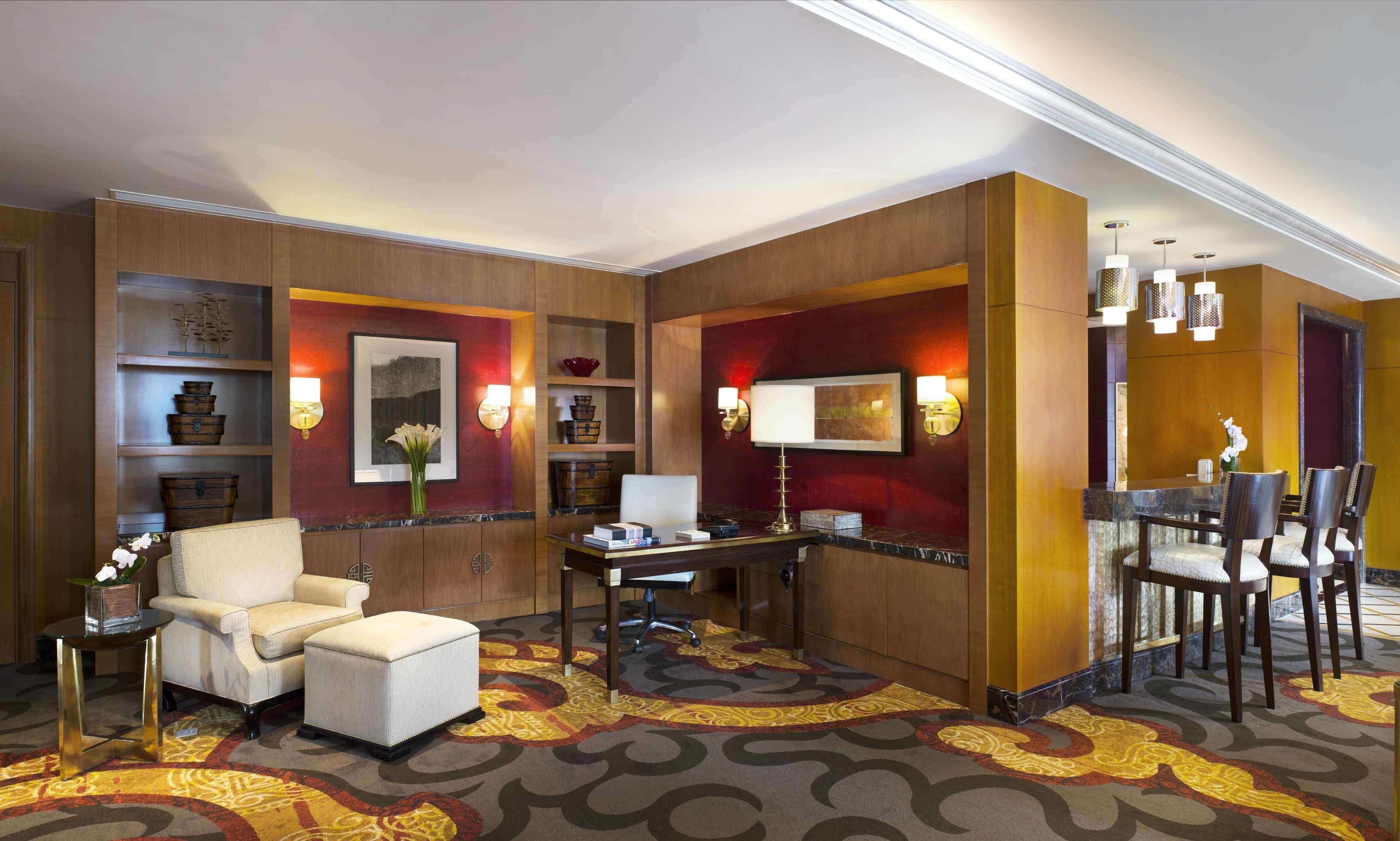 Quarto de hotel com área de estar, escrivaninha e mesa de jantar.