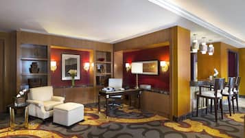 Quarto de hotel com área de estar, escrivaninha e mesa de jantar.