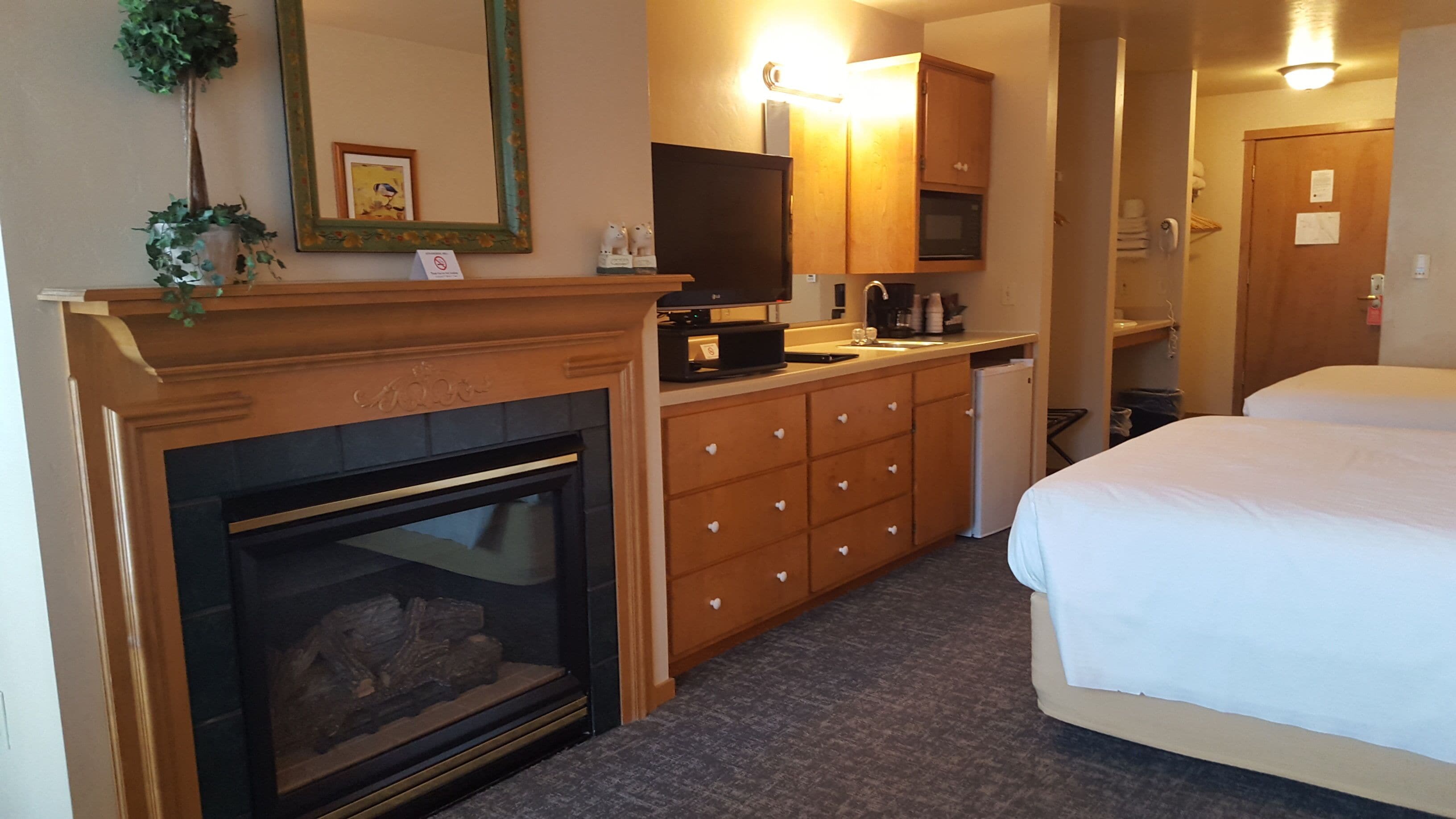 Quarto de hotel com lareira, cómoda de madeira, cama e televisão.