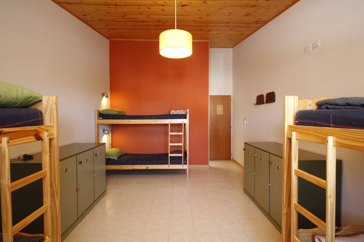 Um quarto de dormitório com beliches, uma escrivaninha e um guarda-roupa.