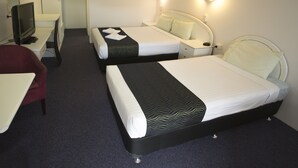 Quarto de hotel com duas camas, uma escrivaninha, uma cadeira e uma televisão.