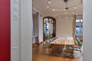 Uma sala de conferência com uma mesa comprida, cadeiras e um candelabro.
