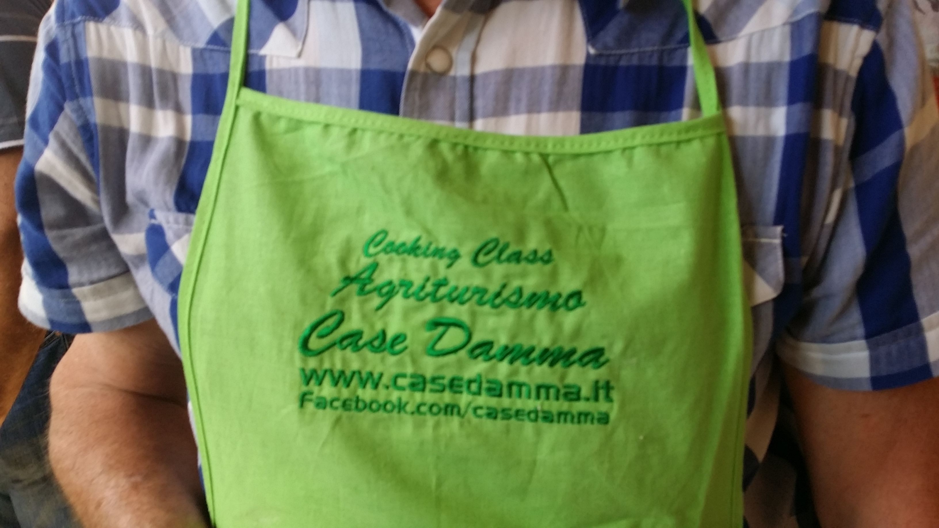 Uma pessoa usando avental verde com texto e endereço de website.