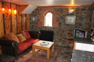 Uma sala de estar aconchegante com um sofá de madeira, uma mesa de centro e uma parede de pedra com uma janela.
