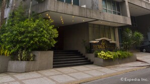 Um hotel de vários andares com design moderno, apresentando varandas e uma entrada destacada com a placa 'HERALD SUITES'.